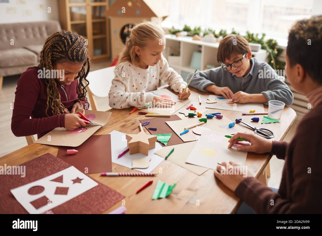 Multi-ethnic group of children making handmade Christmas cards together ...