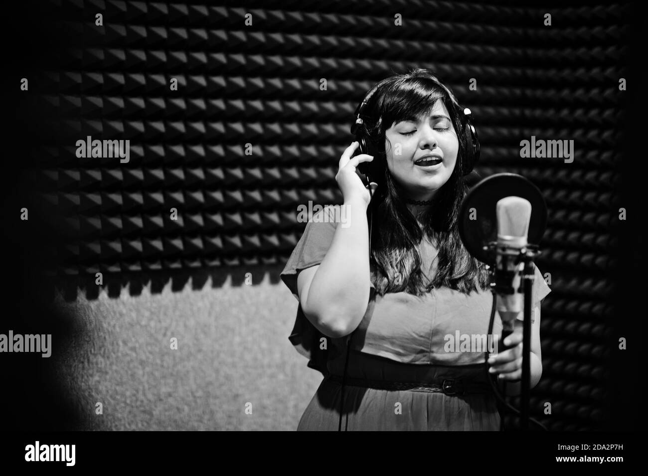 Young asian singer with microphone recording song in record music ...