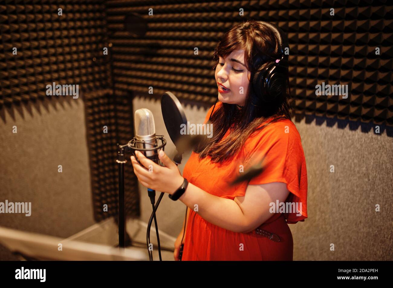 Young asian singer with microphone recording song in record music ...