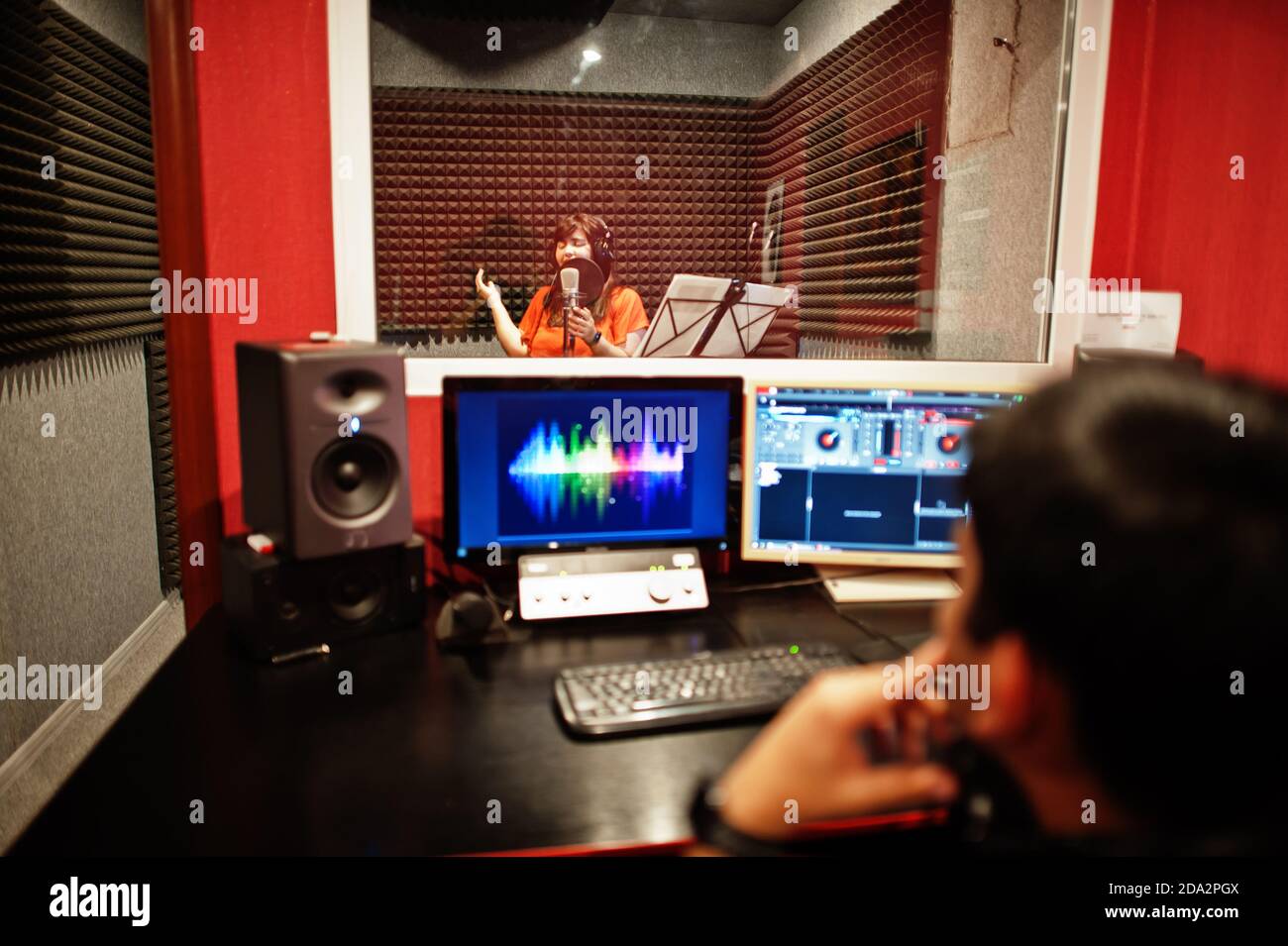 Young asian singer with microphone recording song in record music ...