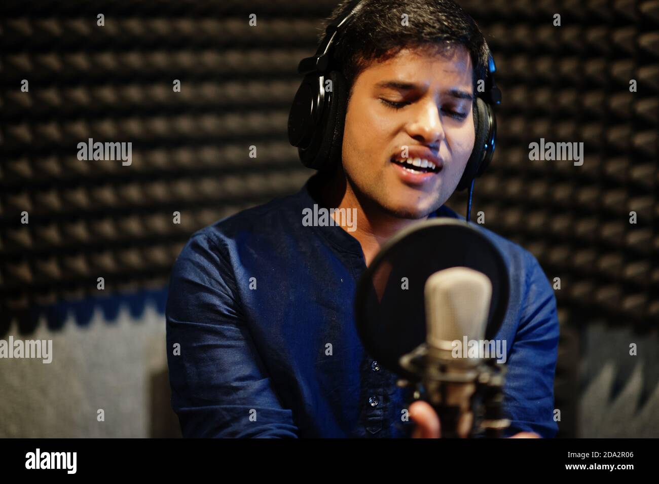 Young asian singer man with microphone recording song in record music ...