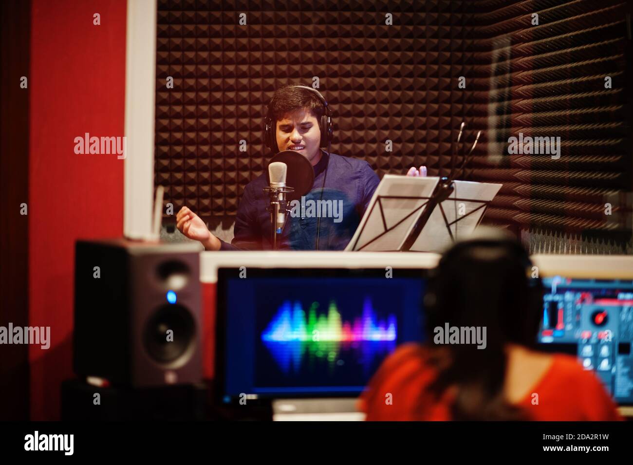 Young asian singer man with microphone recording song in record music ...