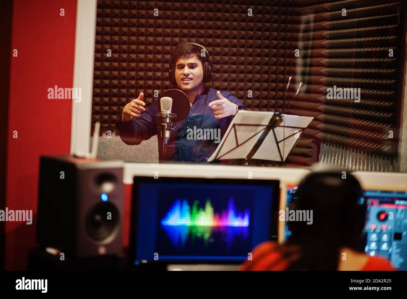 Young asian singer man with microphone recording song in record music ...
