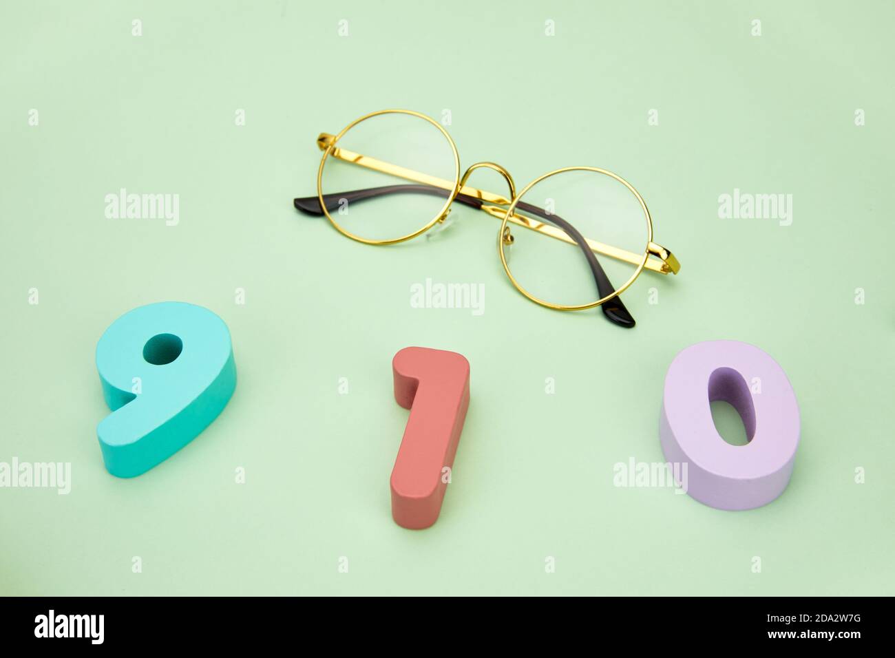 Top view of 910 numbers with eyeglasses on a light green surface Stock ...