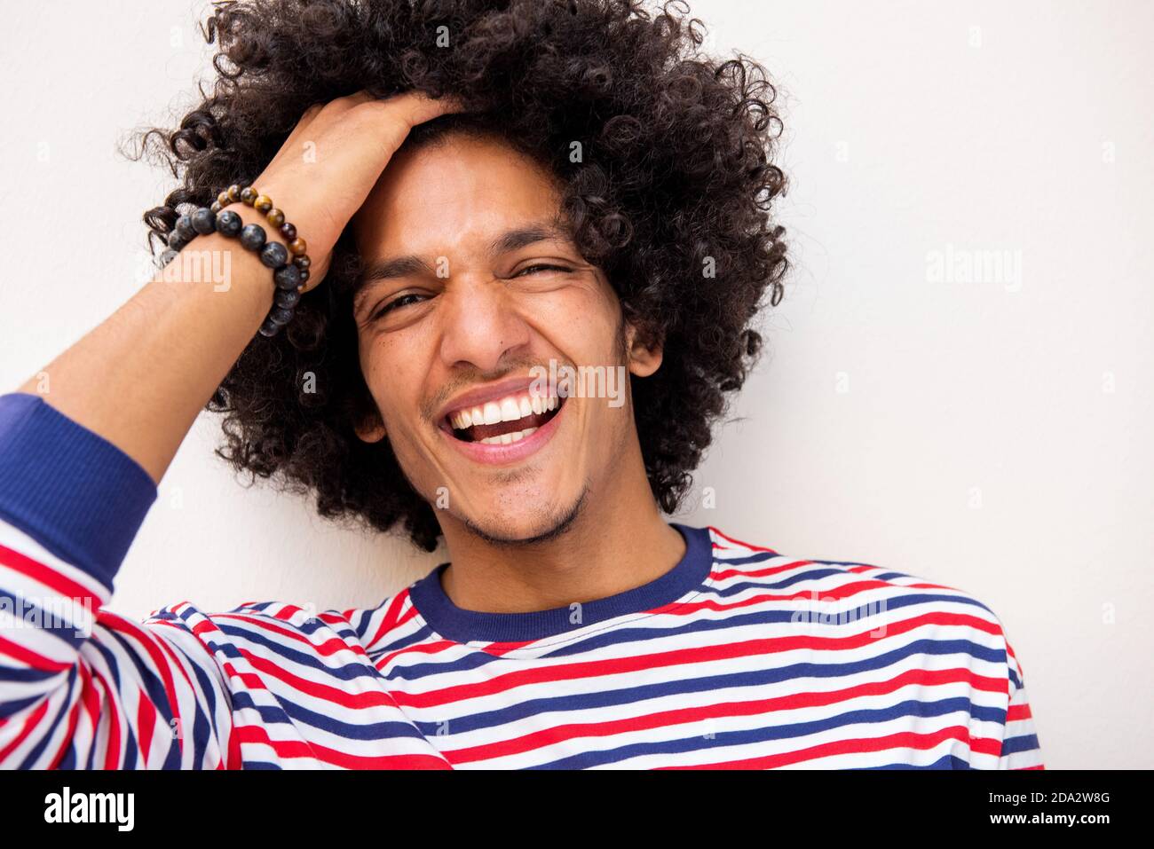 Close up portrait laughing young arabic man with hand in afro hair by ...