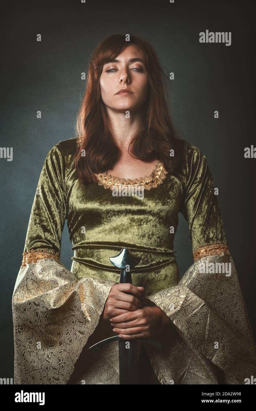 Medieval queen with sword and eyes closed. Red haired woman Stock Photo ...