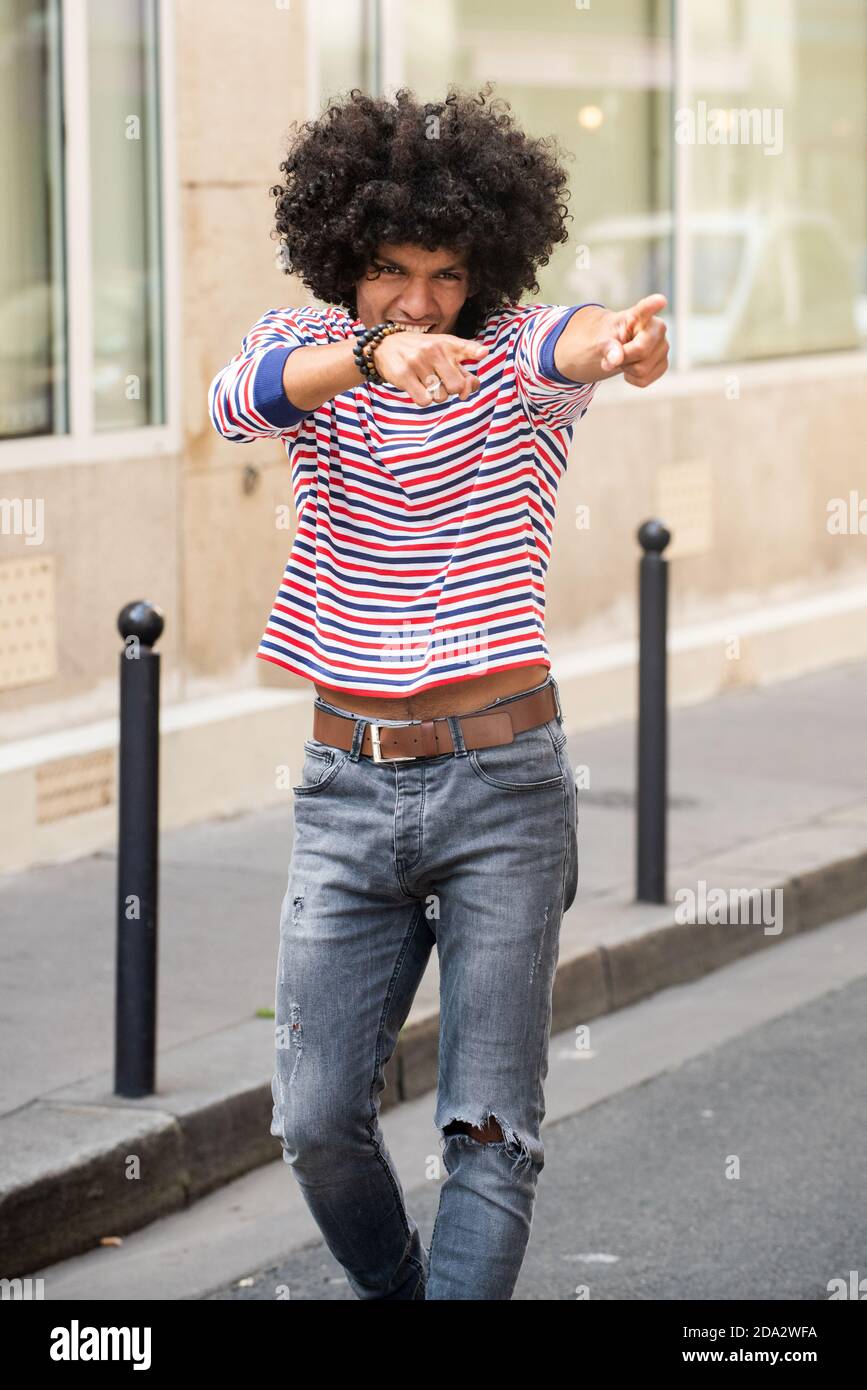 Portrait cool young arabic man walking on city street and pointing ...