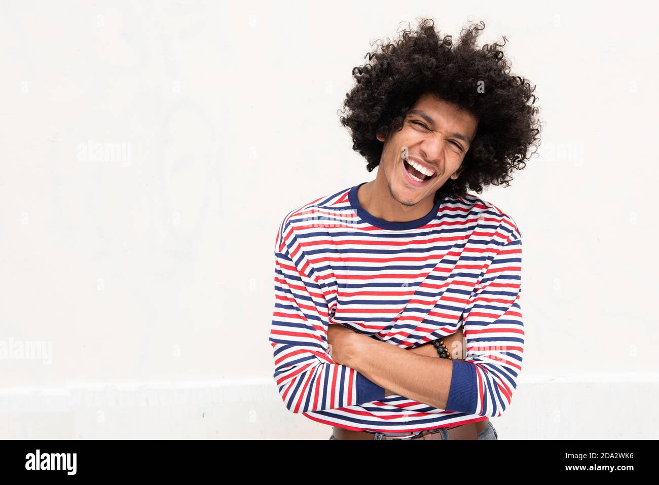 Portrait cool young arabic man laughing with arms crossed against ...