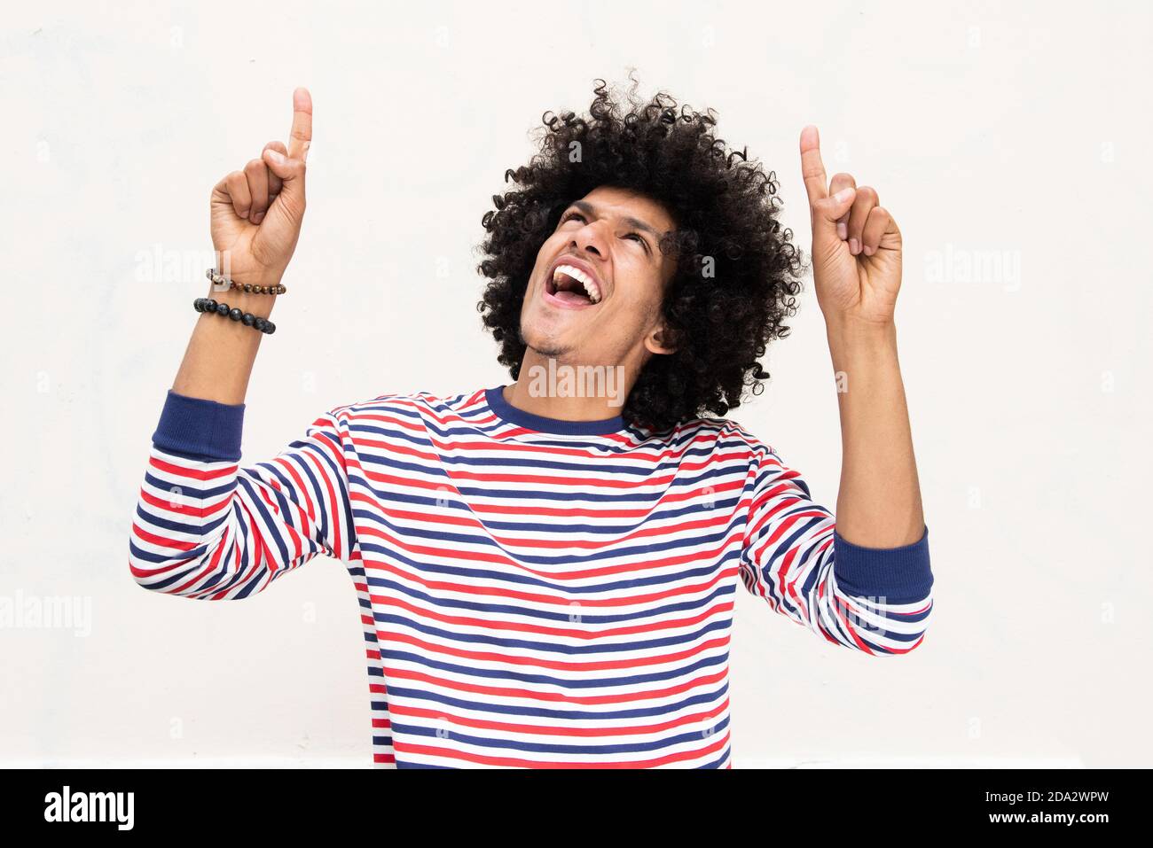 Portrait cool young arabic man laughing with arms raised and pointing ...