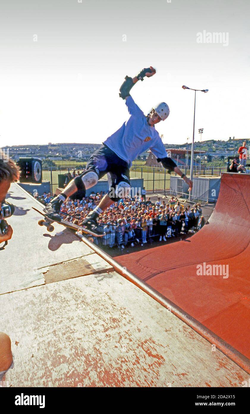 Pro skater Tony Hawk grinding the coping on the huge halfpipe ramp ...