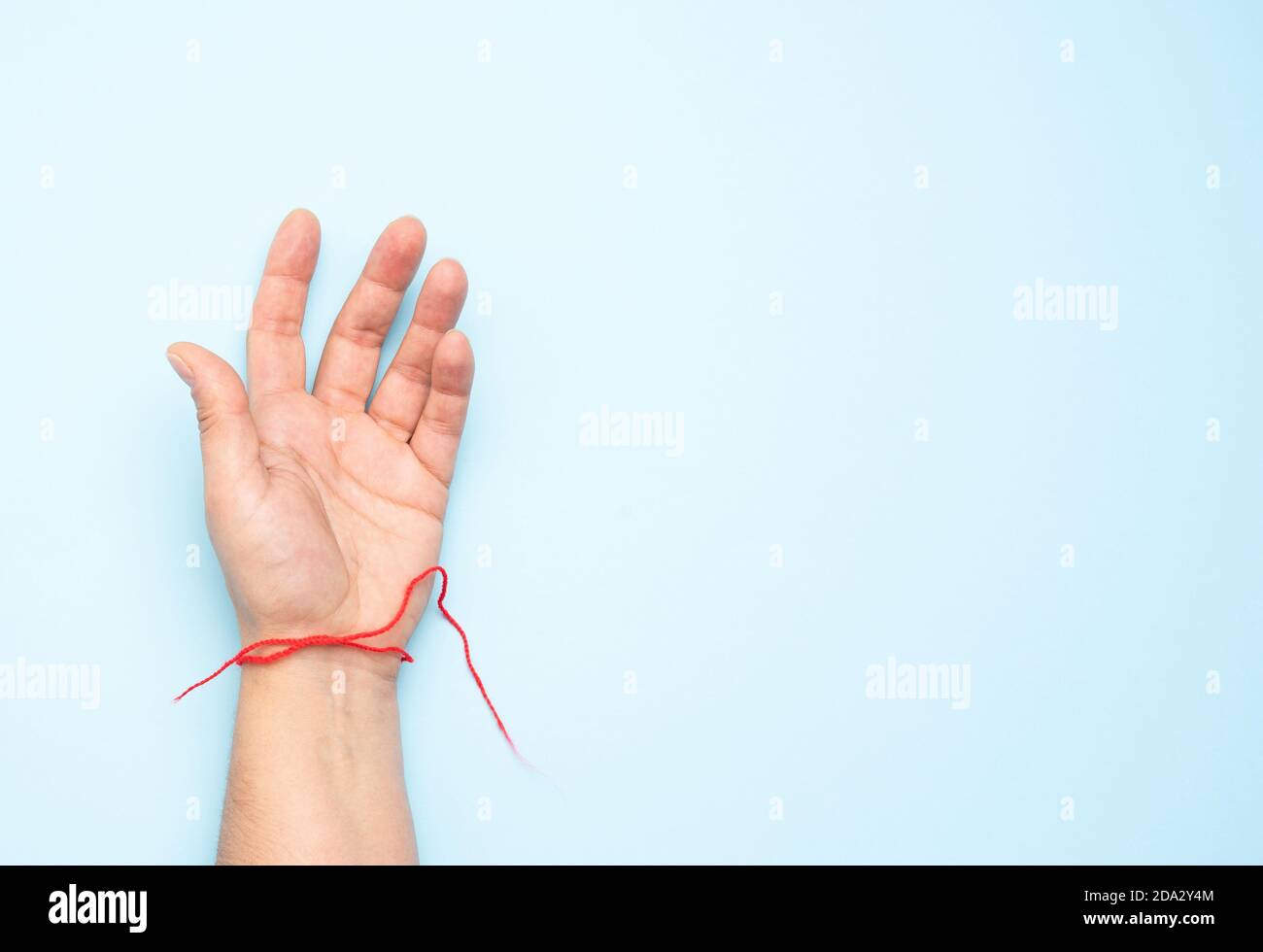 red woolen thread on the wrist of a female hand, blue background, copy ...