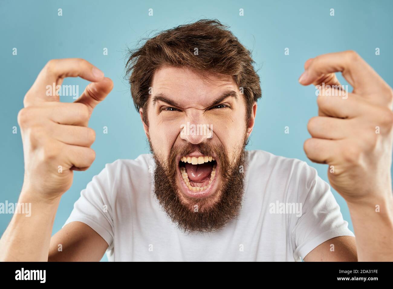Bearded man in white T-shirt emotions gestures with hands displeased ...
