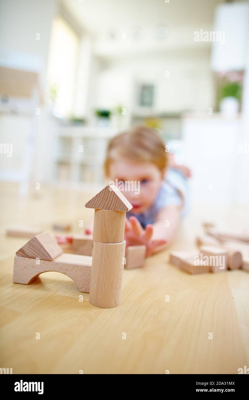 Child builds a house with wooden building blocks on the floor Stock ...