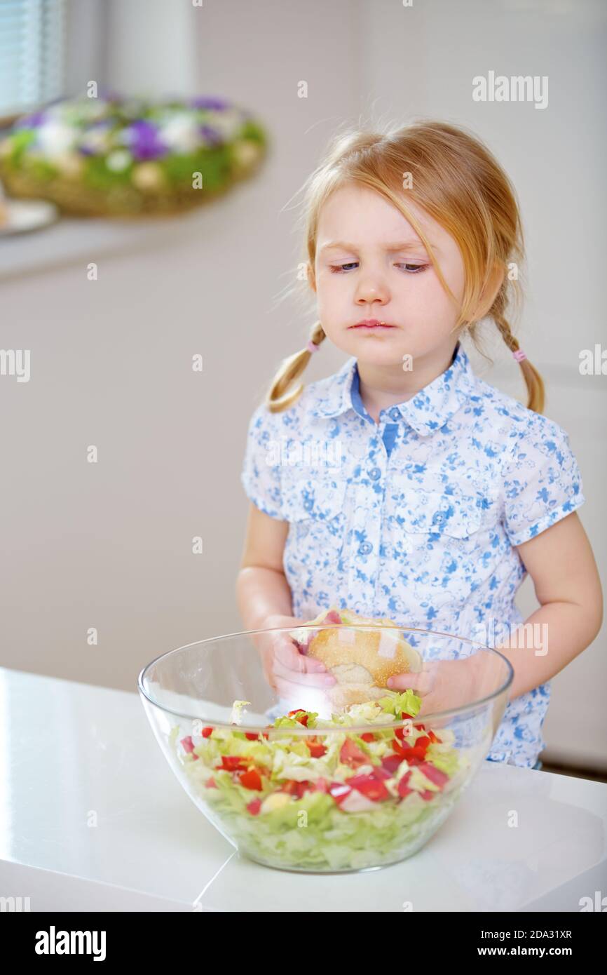 Child bites off a sandwich in the kitchen next to a salad Stock Photo ...