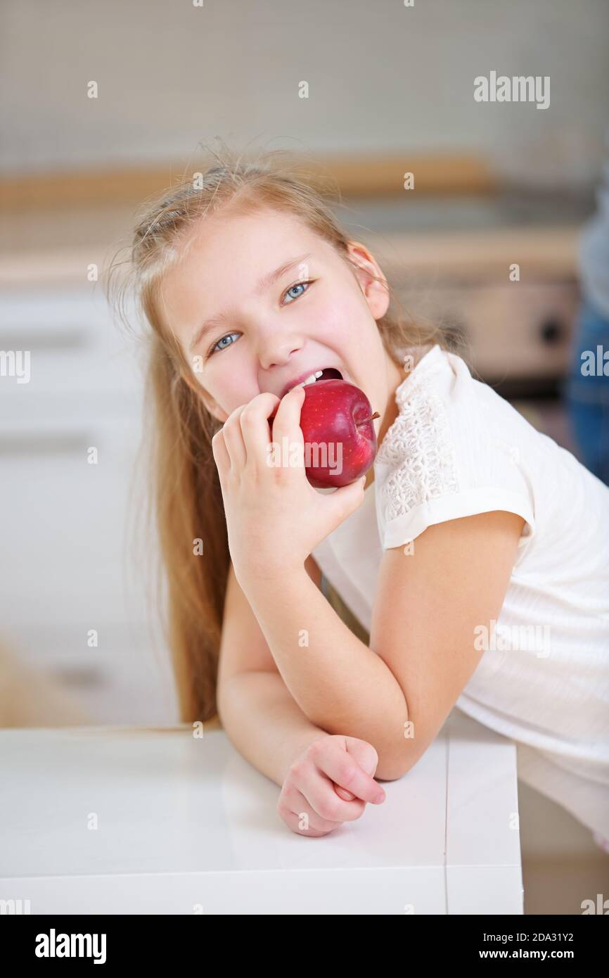 Child bites into a red apple at home in the kitchen Stock Photo - Alamy