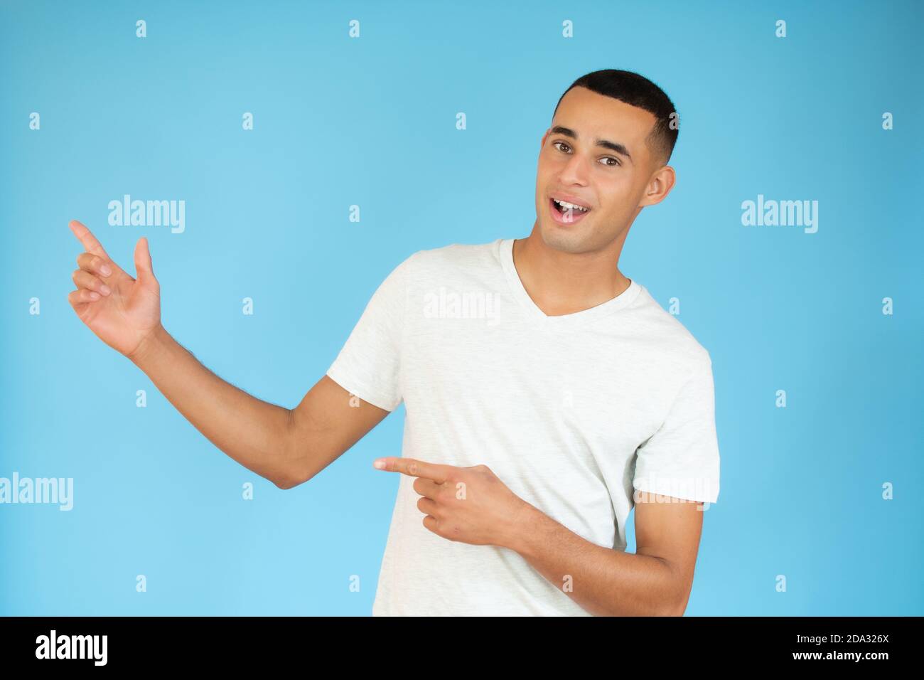 friendly young man pointing to his side and looking into the camera ...