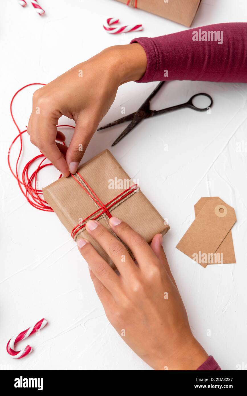 Female's hands wrapping Christmas gift boxes decorated with kraft paper ...