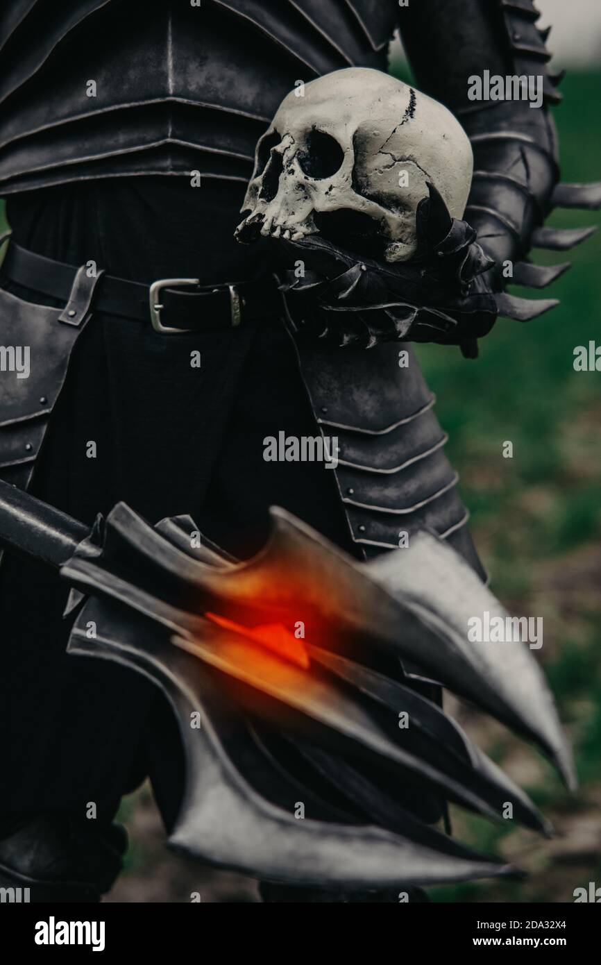 Warrior in armor stands with glowing mace and human skull in his hands ...