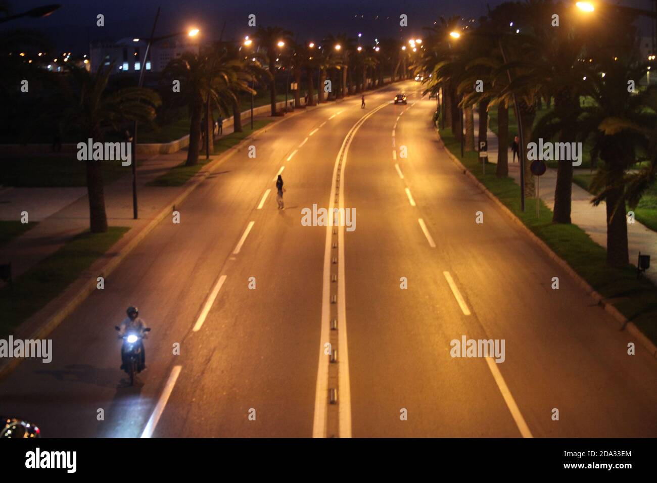 empty lighted street at night, trafic road with yellow lamp post lights ...