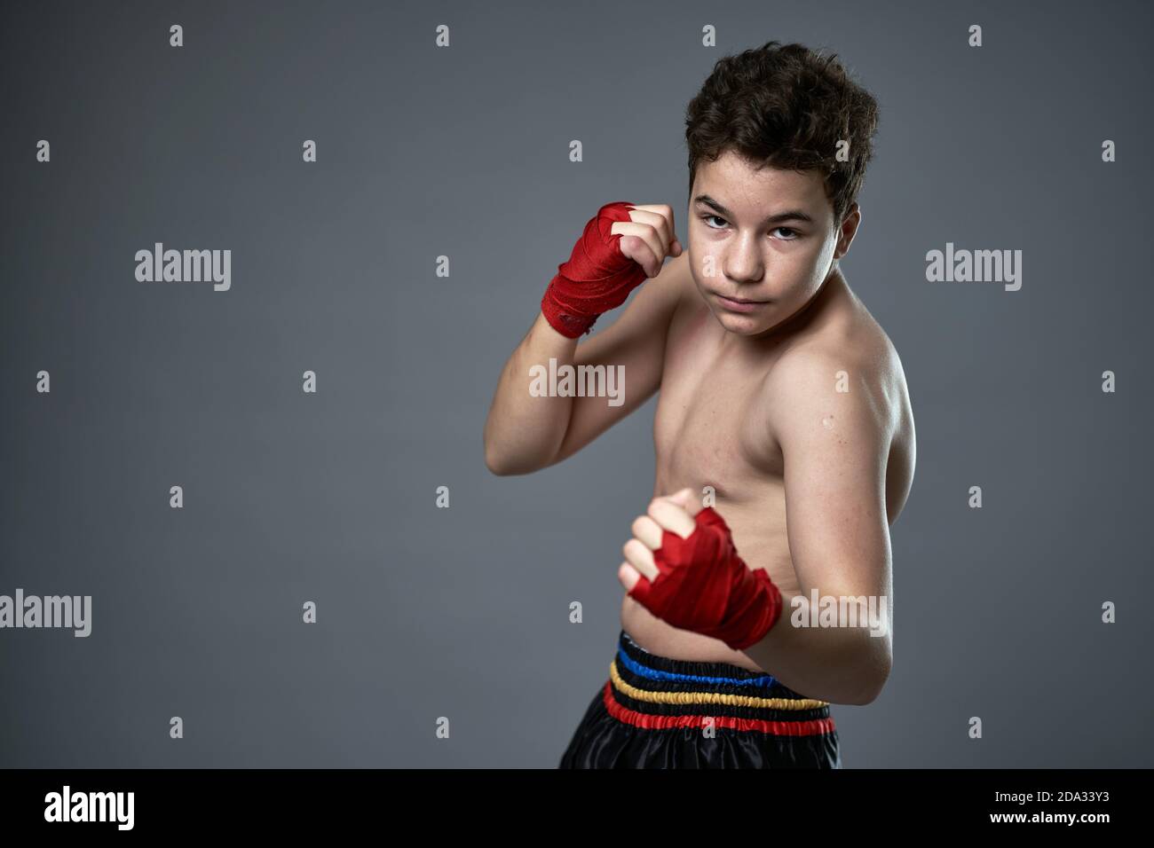 Young kickboxer with hands wrapped training in shadow boxing against ...