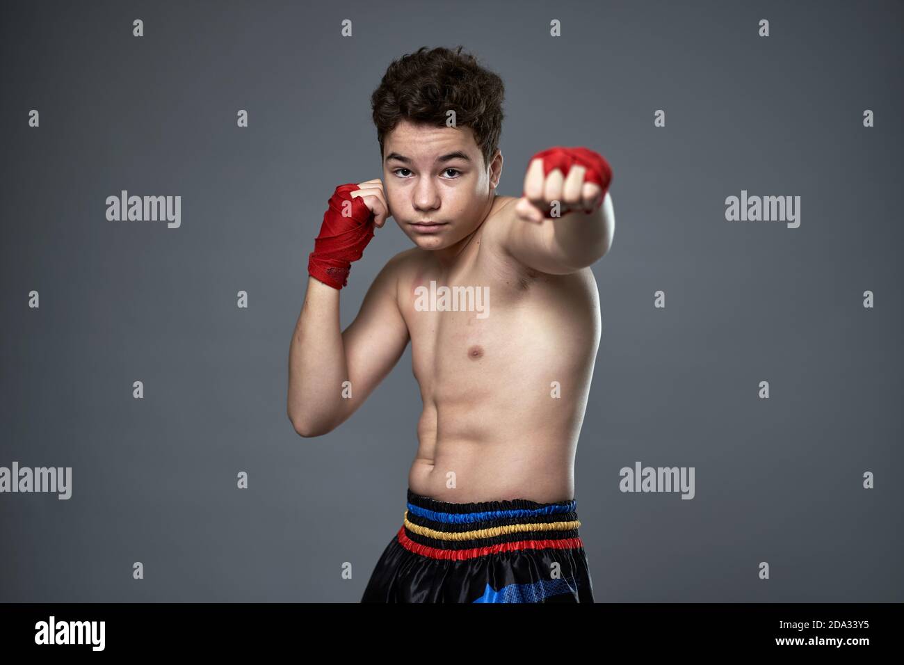 Young kickboxer with hands wrapped training in shadow boxing against ...