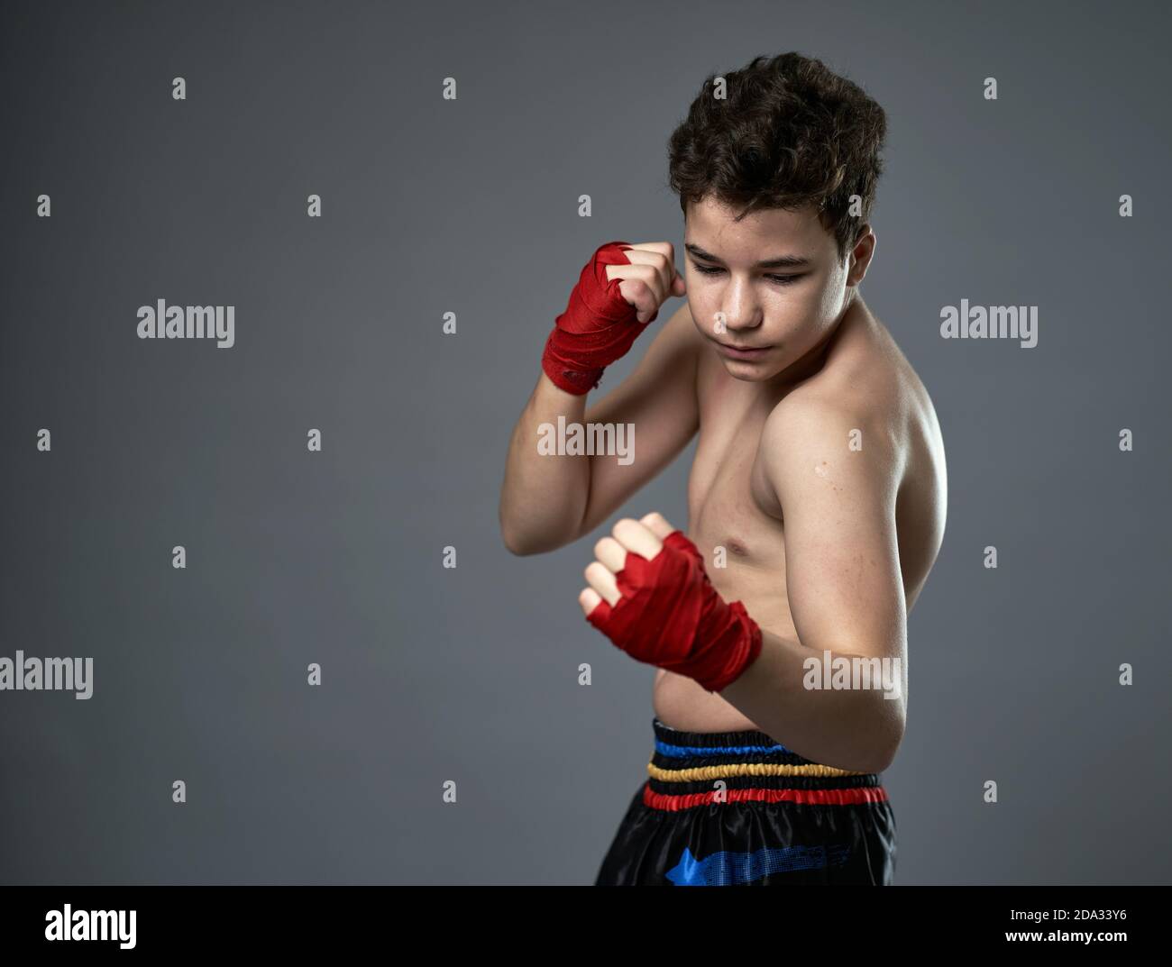 Young kickboxer with hands wrapped training in shadow boxing against ...