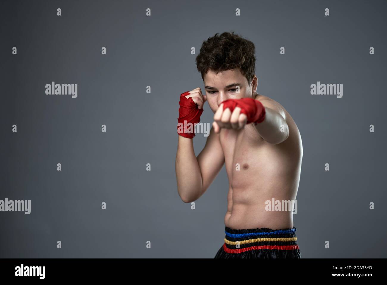 Young kickboxer with hands wrapped training in shadow boxing against ...