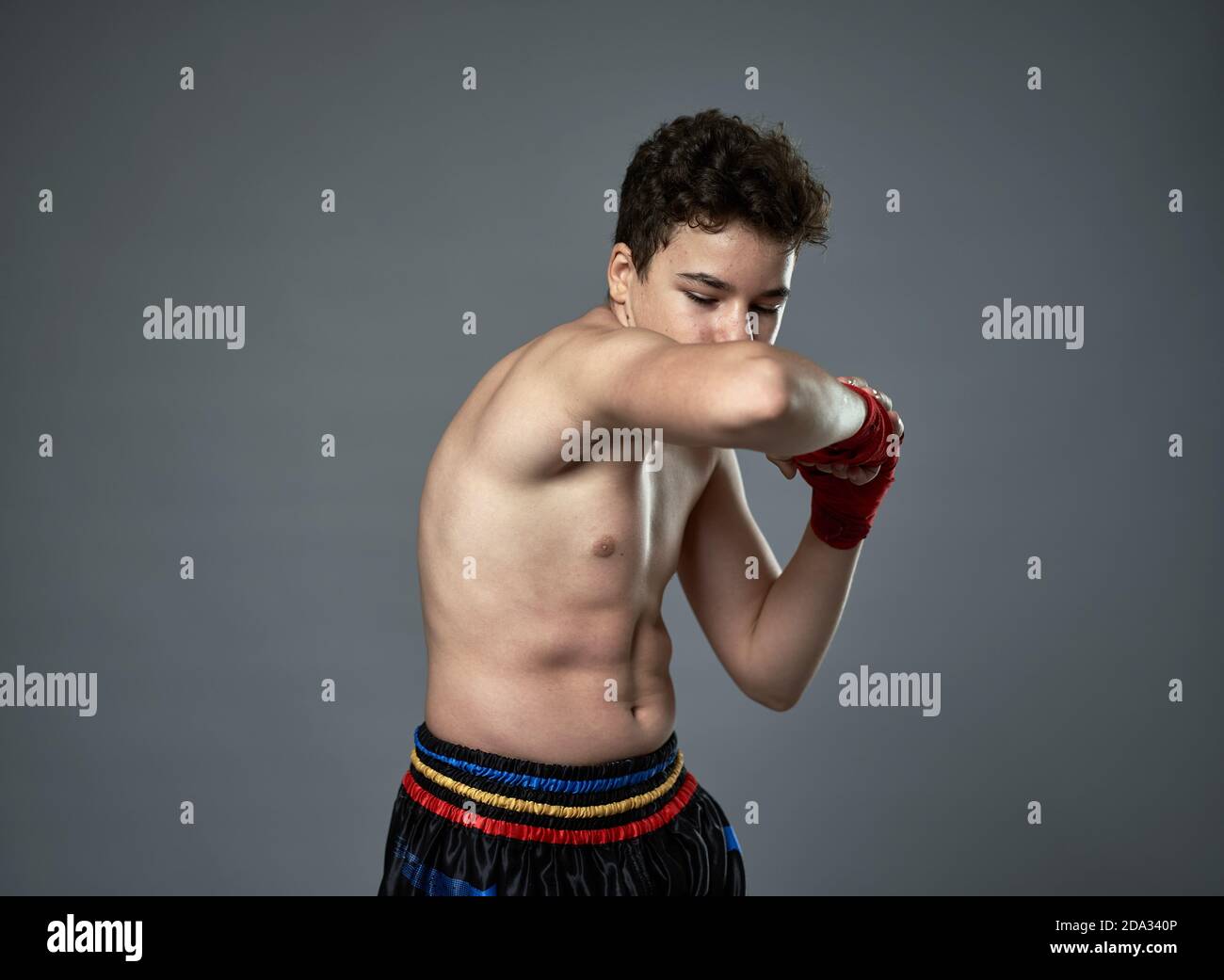 Young kickboxer with hands wrapped training in shadow boxing against ...