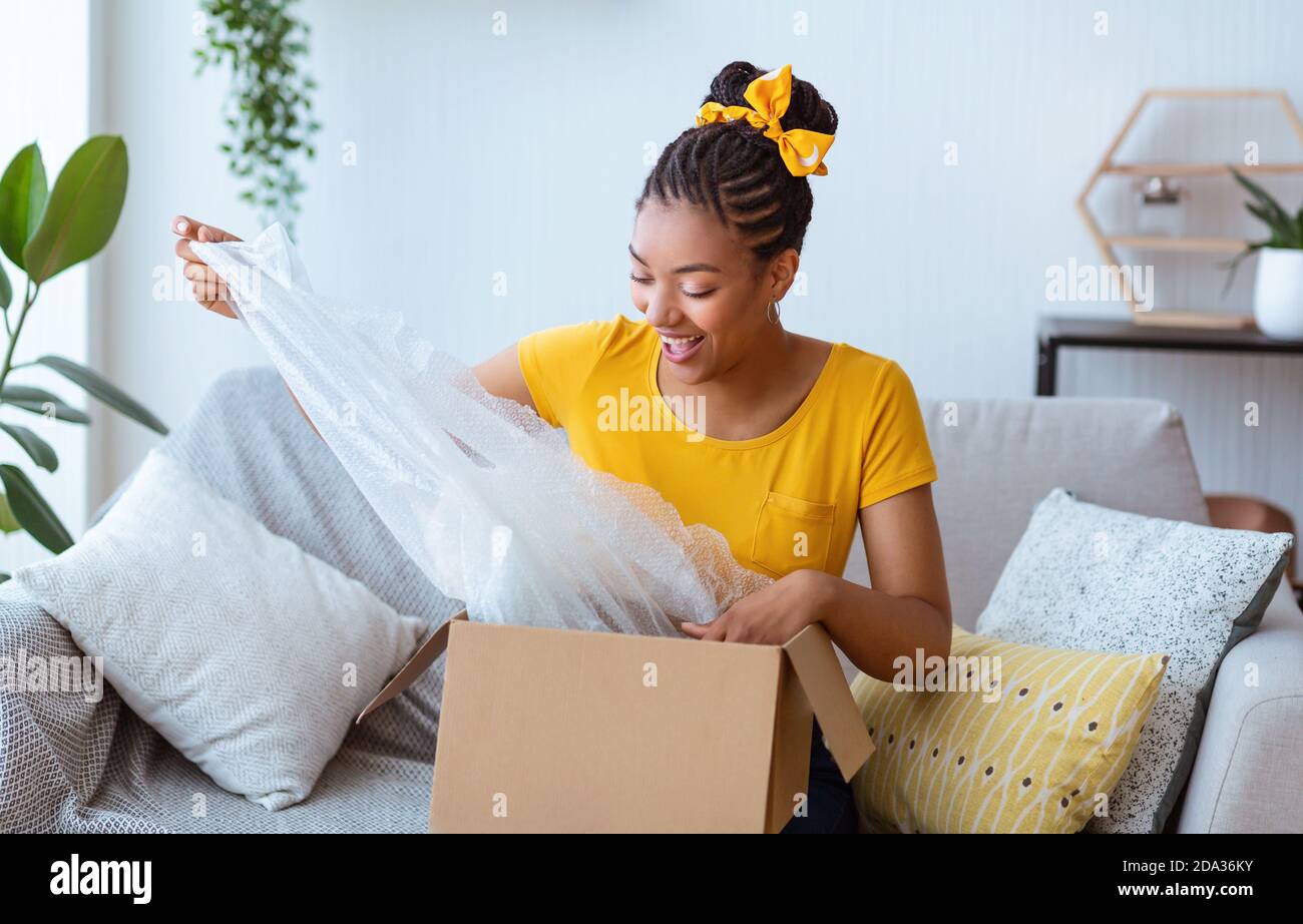 Happy black lady unpacking box after online shopping Stock Photo - Alamy
