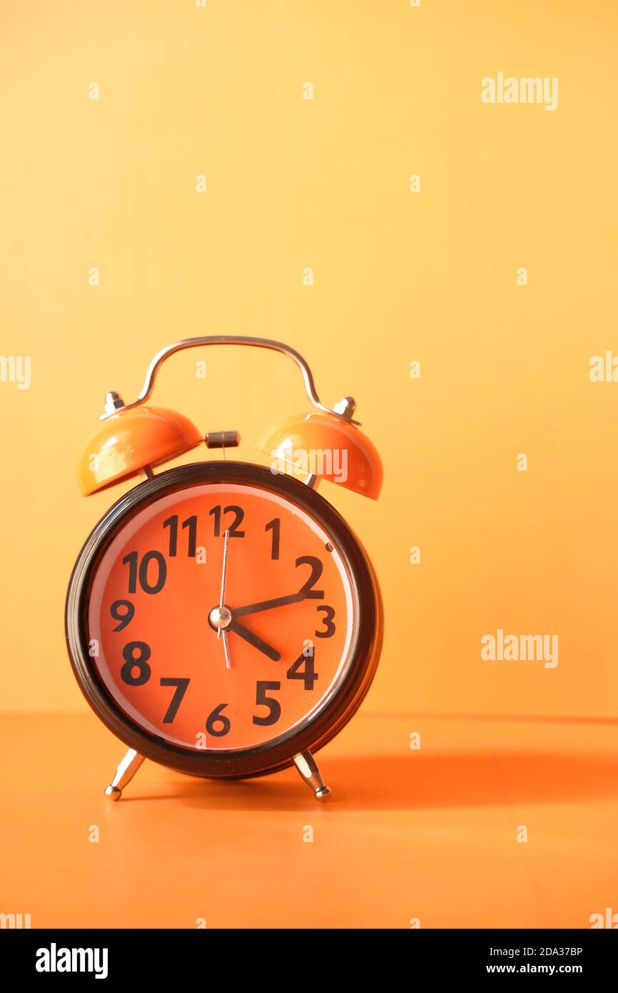 old alarm clock on orange background Stock Photo - Alamy