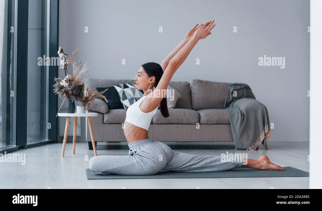 Does flexible exercises. Young woman with slim body shape in sportswear ...