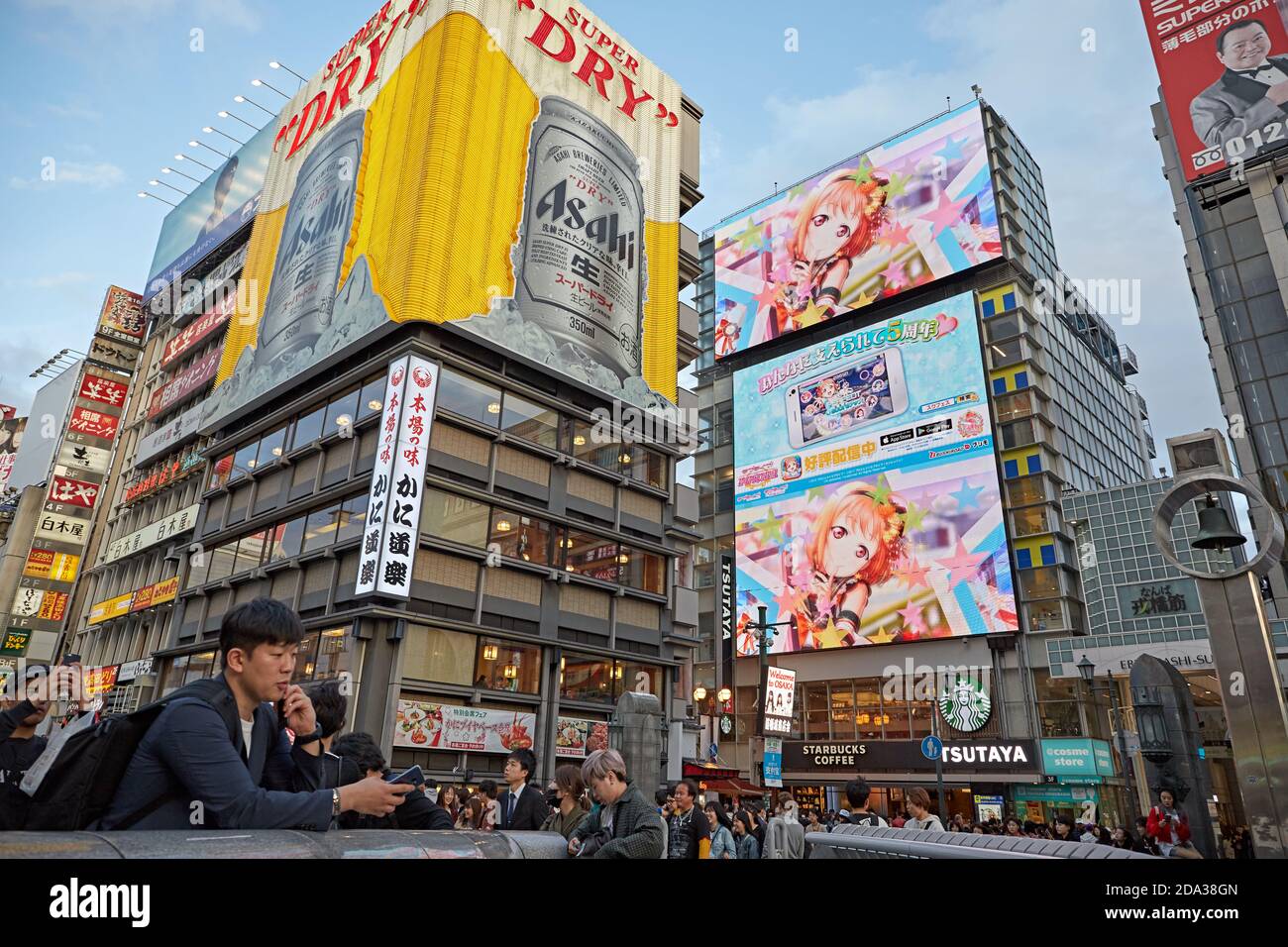 Osaka, Japan, April 2018. A man watching his mobile on the Ebisu Bridge with luminous signs in ...