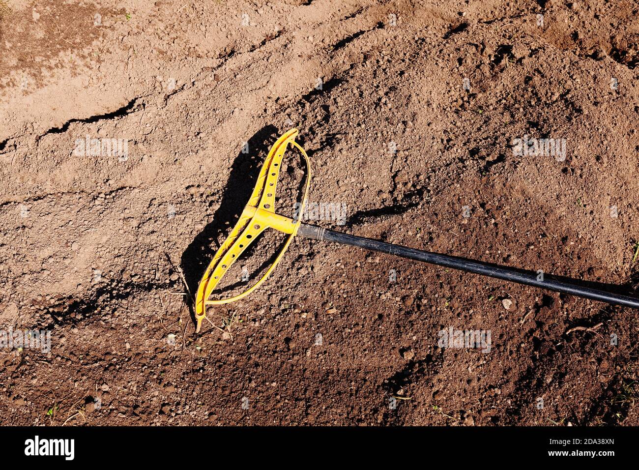Bright yellow garden rake lying on fresh soil in garden Stock Photo - Alamy