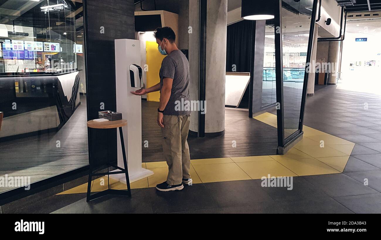 Man wearing protective face mask uses automatic hand sanitizer ...
