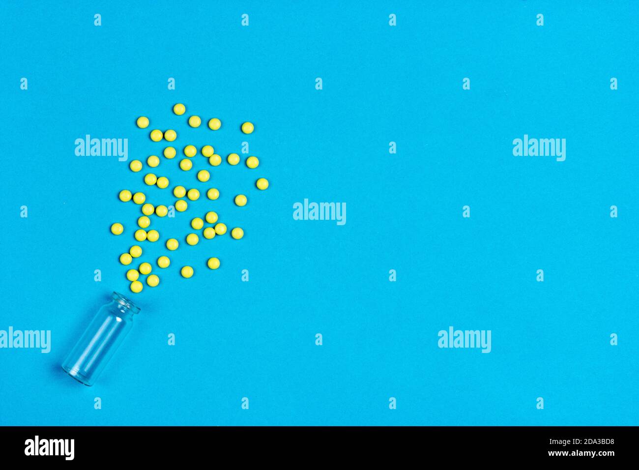 Empty medical jar and yellow medical pills, pills scattered on a blue ...