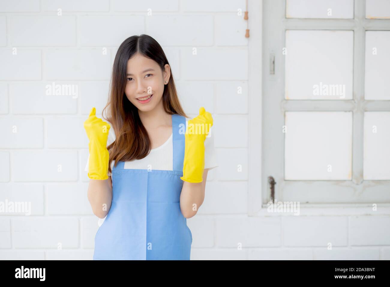 Portrait young asian woman is housekeeper in rubber gloves and apron ...