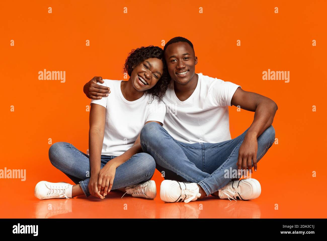 Carefree african couple sitting on floor and hugging Stock Photo - Alamy