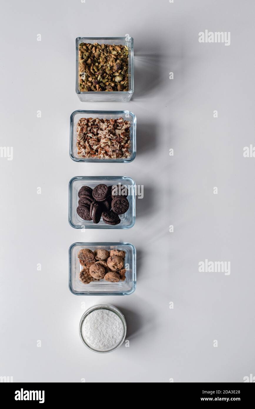 Row of ingredients in small containers with pistachio, nuts, cookies ...