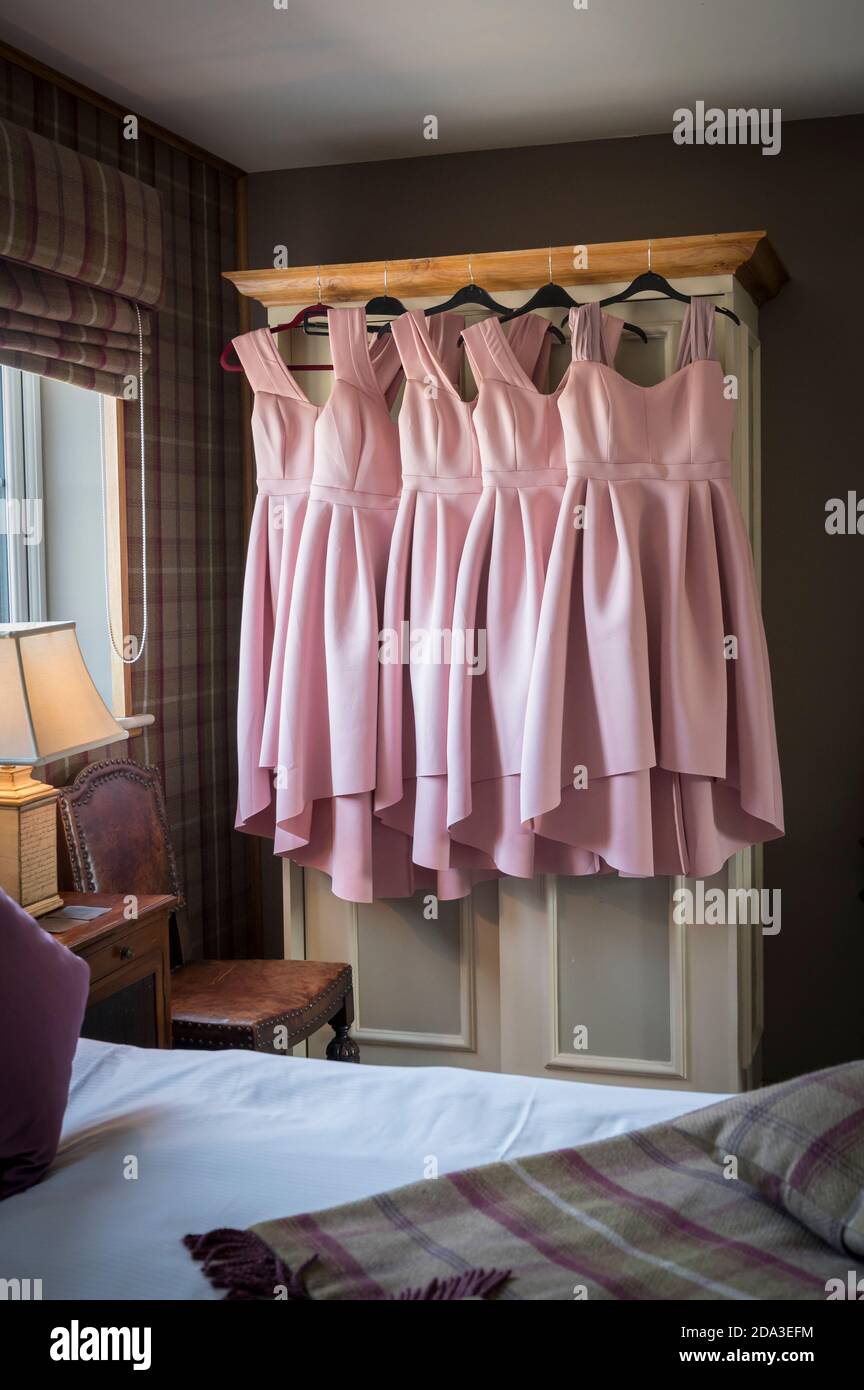 Pink Bridesmaids Dresses Hanging On A Wardrobe Door In A Bedroom Stock