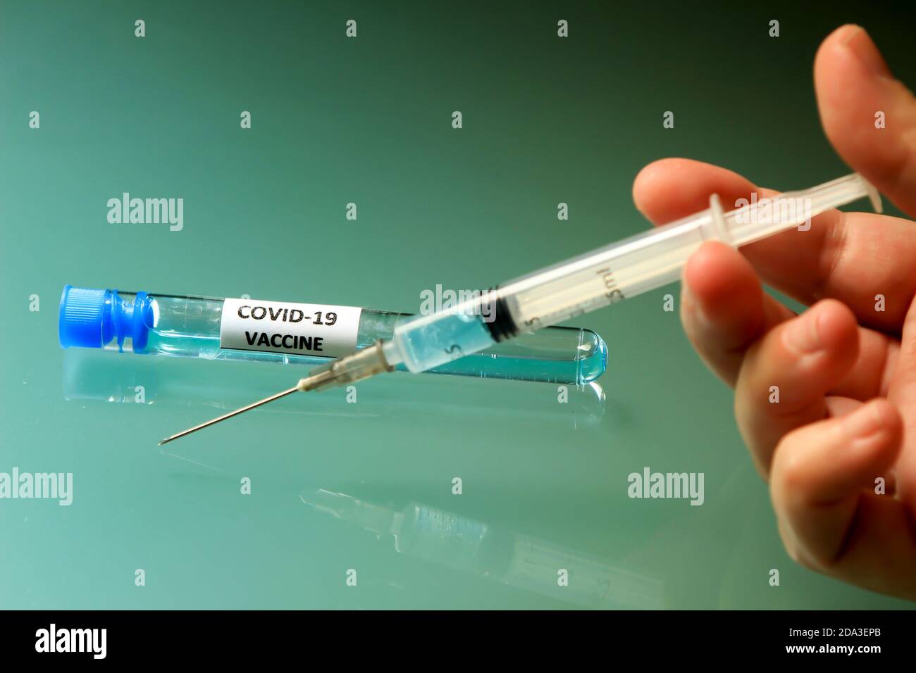 Hand holding Syringe next to test tube with vaccine for Covid-19 virus ...