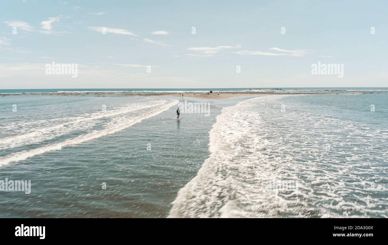 Aerial shot of a person walking on the Whale's tale beach in Costa Rica ...