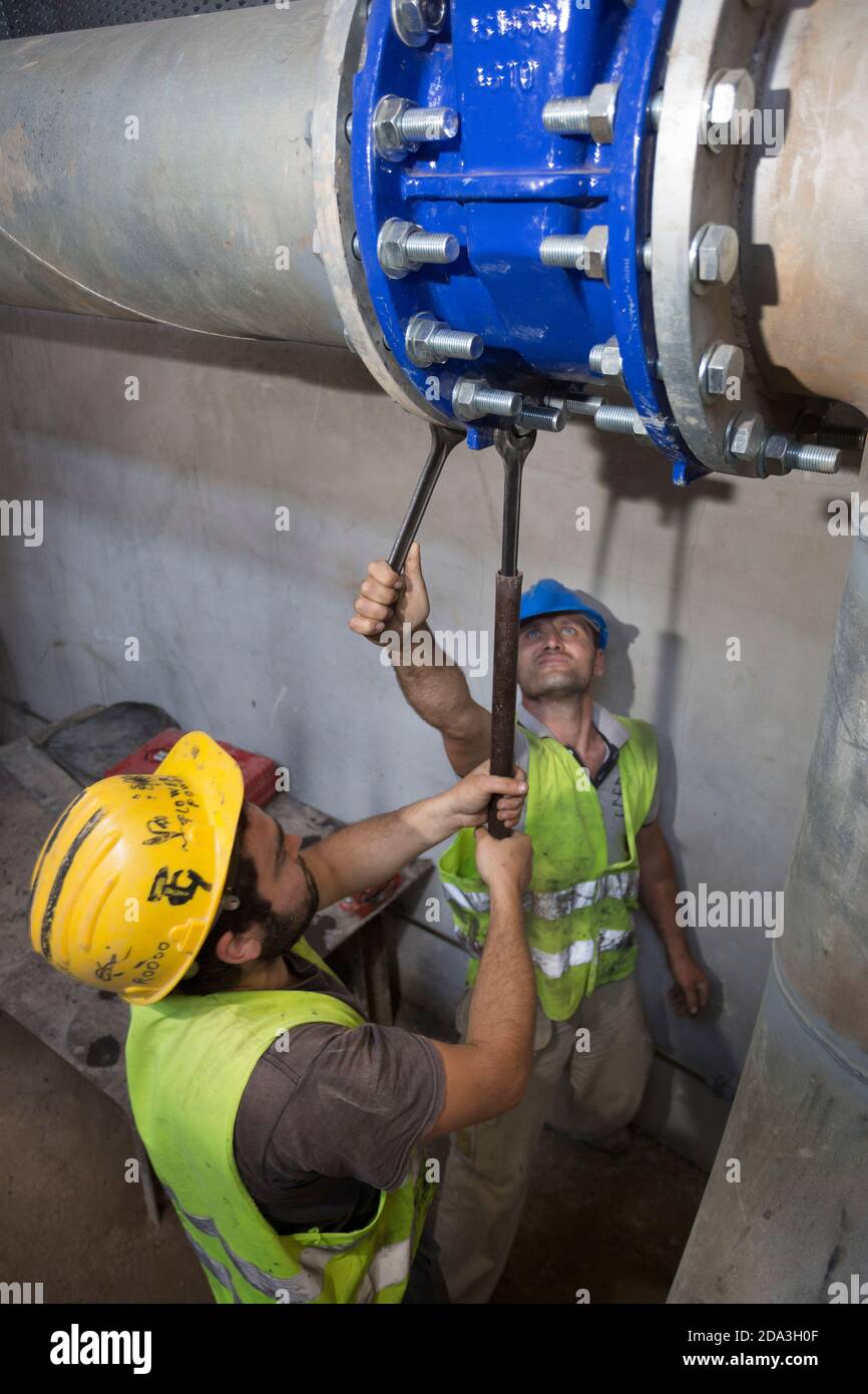 Workers help to construct a new pump house infrastructure as part of ...