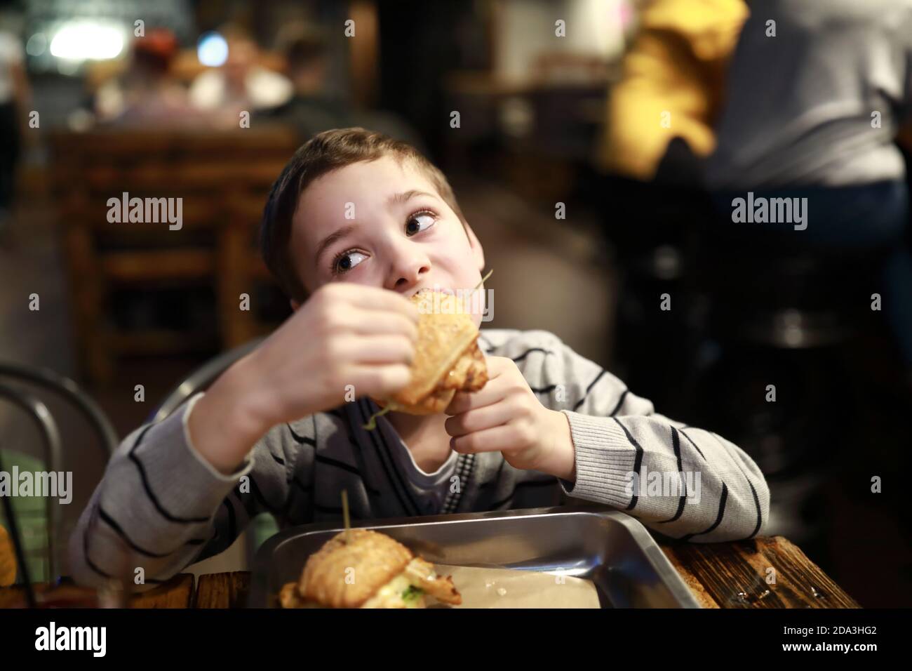 Boy eating a burger in a restaurant Stock Photo - Alamy