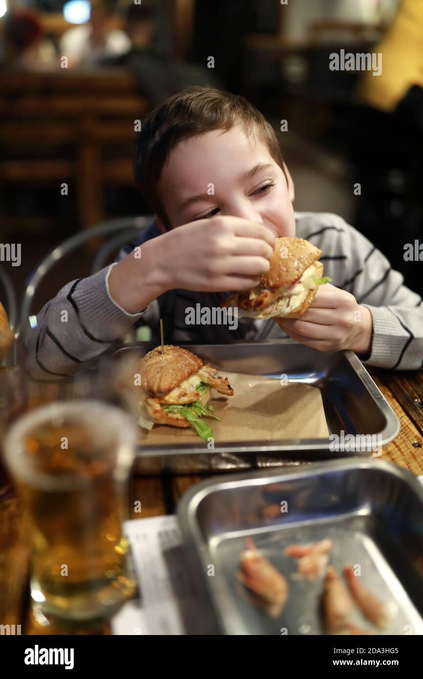 Child eating a burger in a restaurant Stock Photo - Alamy
