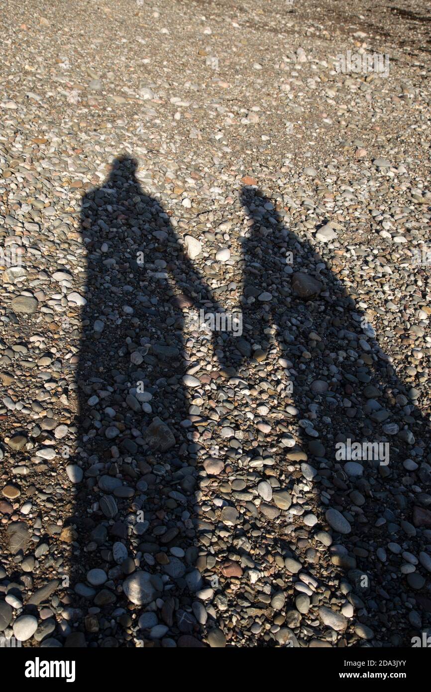 Togetherness. A couple's shadows on the beach holding hands Stock Photo ...