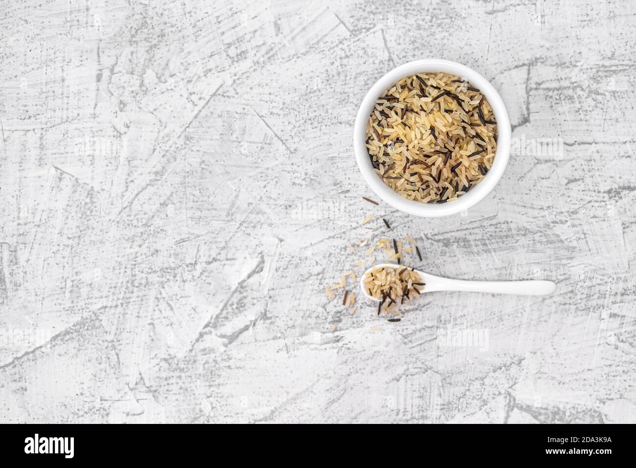 Mixed rice in white plate and spoon on white stone background ...