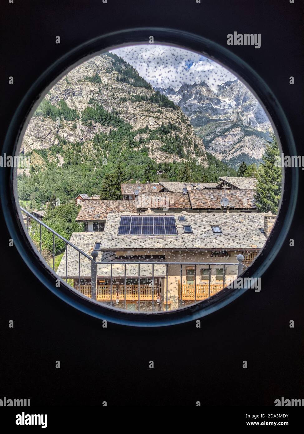 A view on mountains and buildings through a round window of a door ...