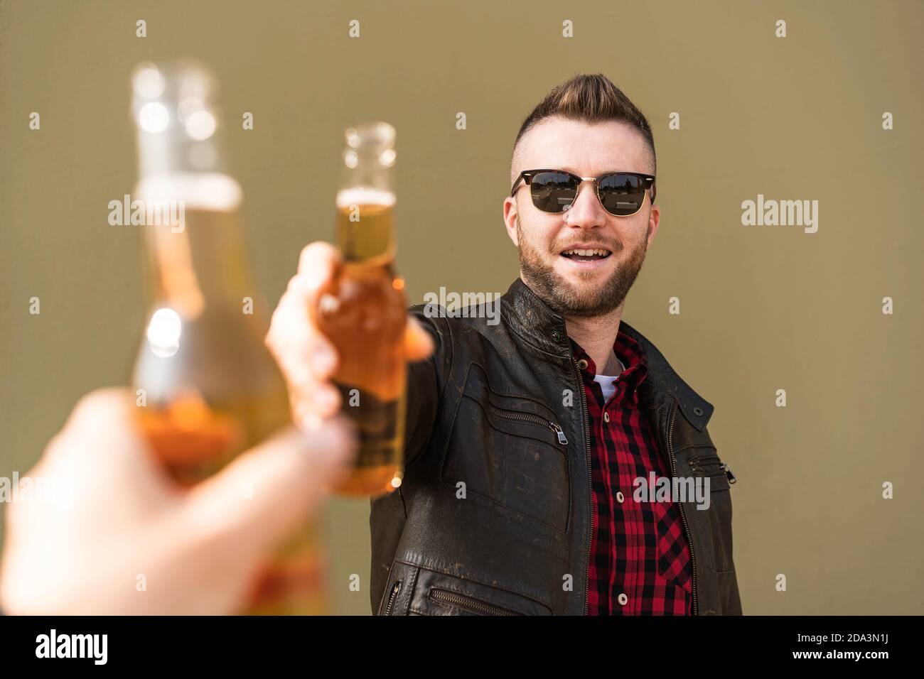 Unshaven cool man toasting beer with best friend outdoor against a ...