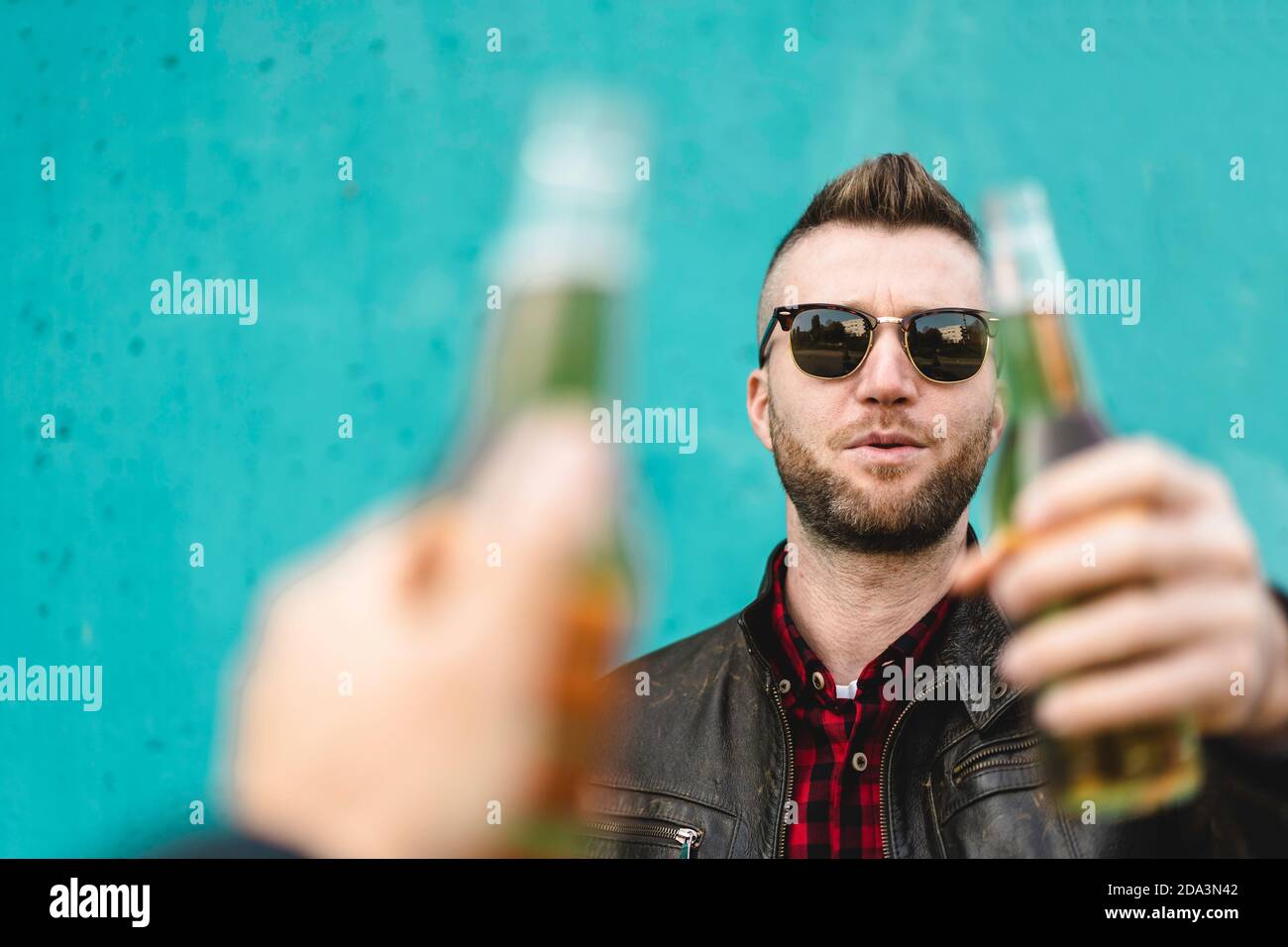 Bearded cool man toasting beer with best friend outdoor against a blue ...