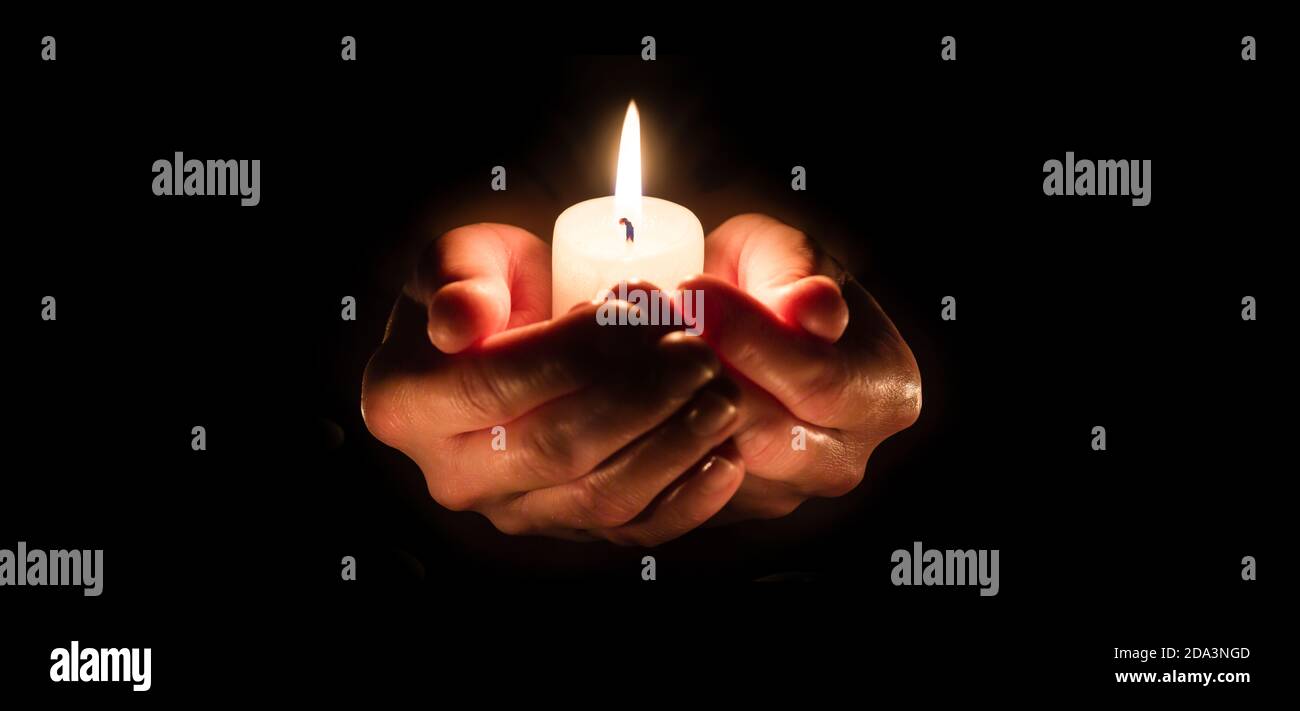 Burning candle in woman hands over black. Religious christmas spa and ...